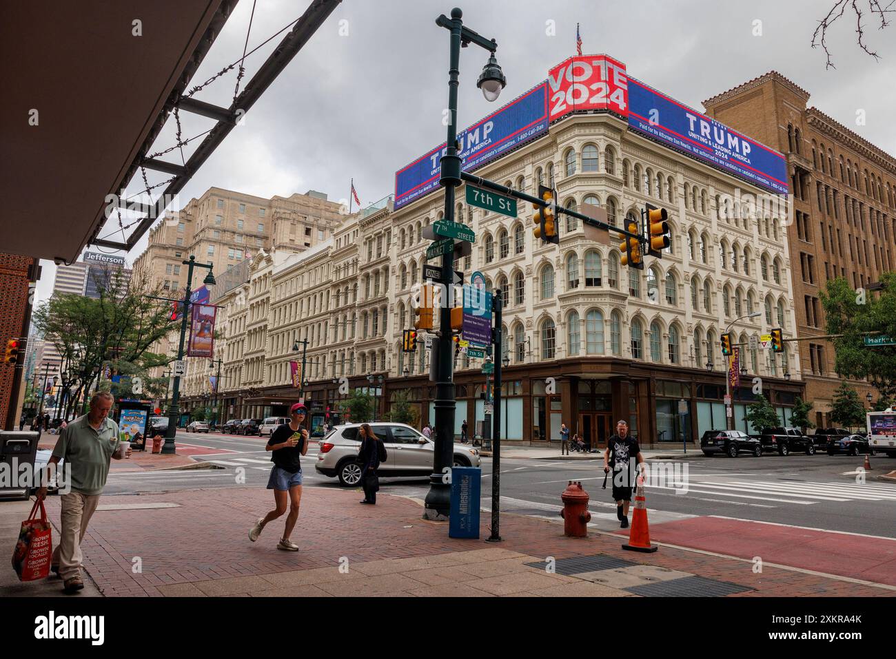 People pass a Trump 2024 advertisement on top of the Lit Brothers ...