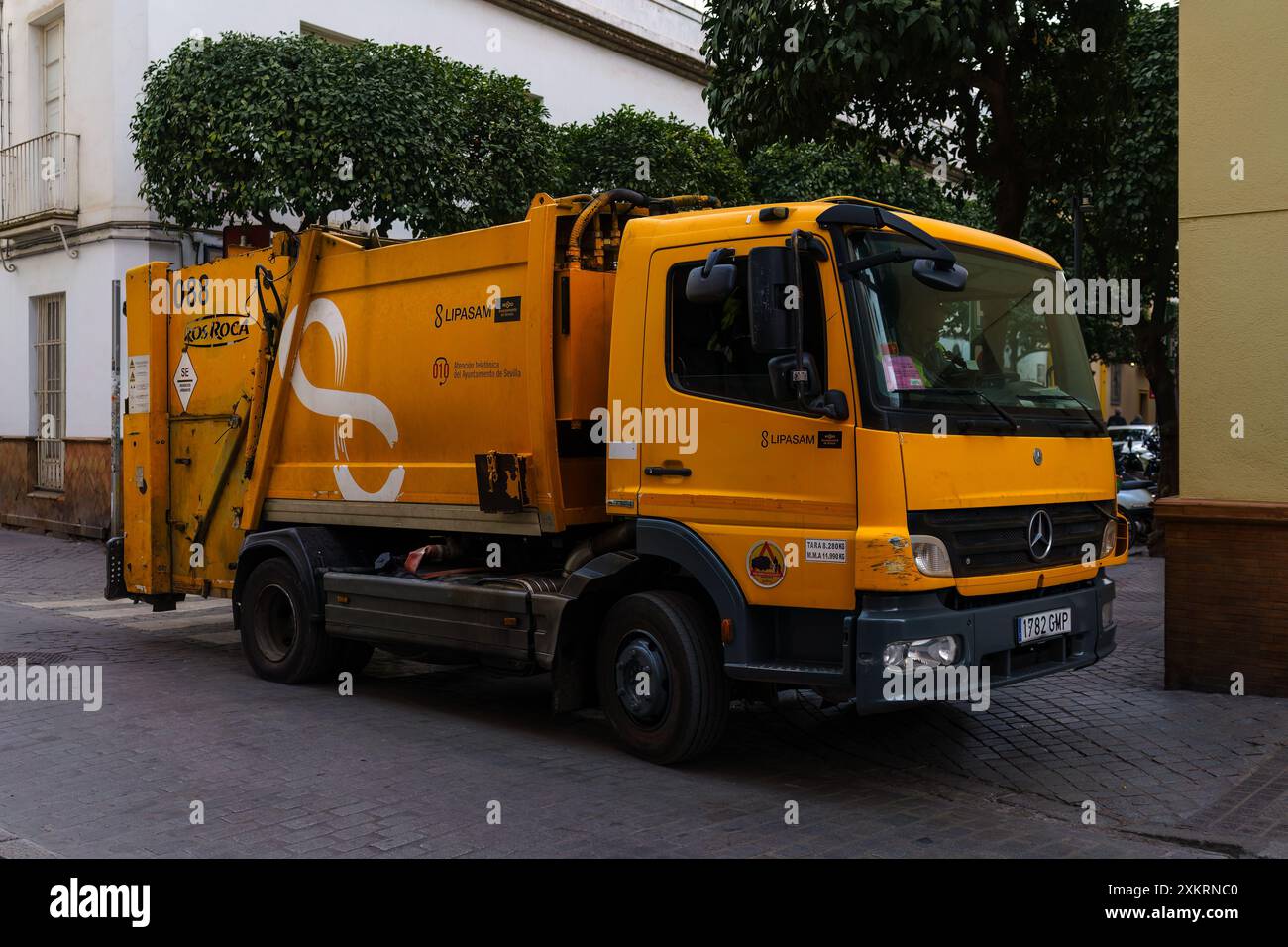 Seville, Spain. February 5, 2024 - Yellow garbage truck in a street ...