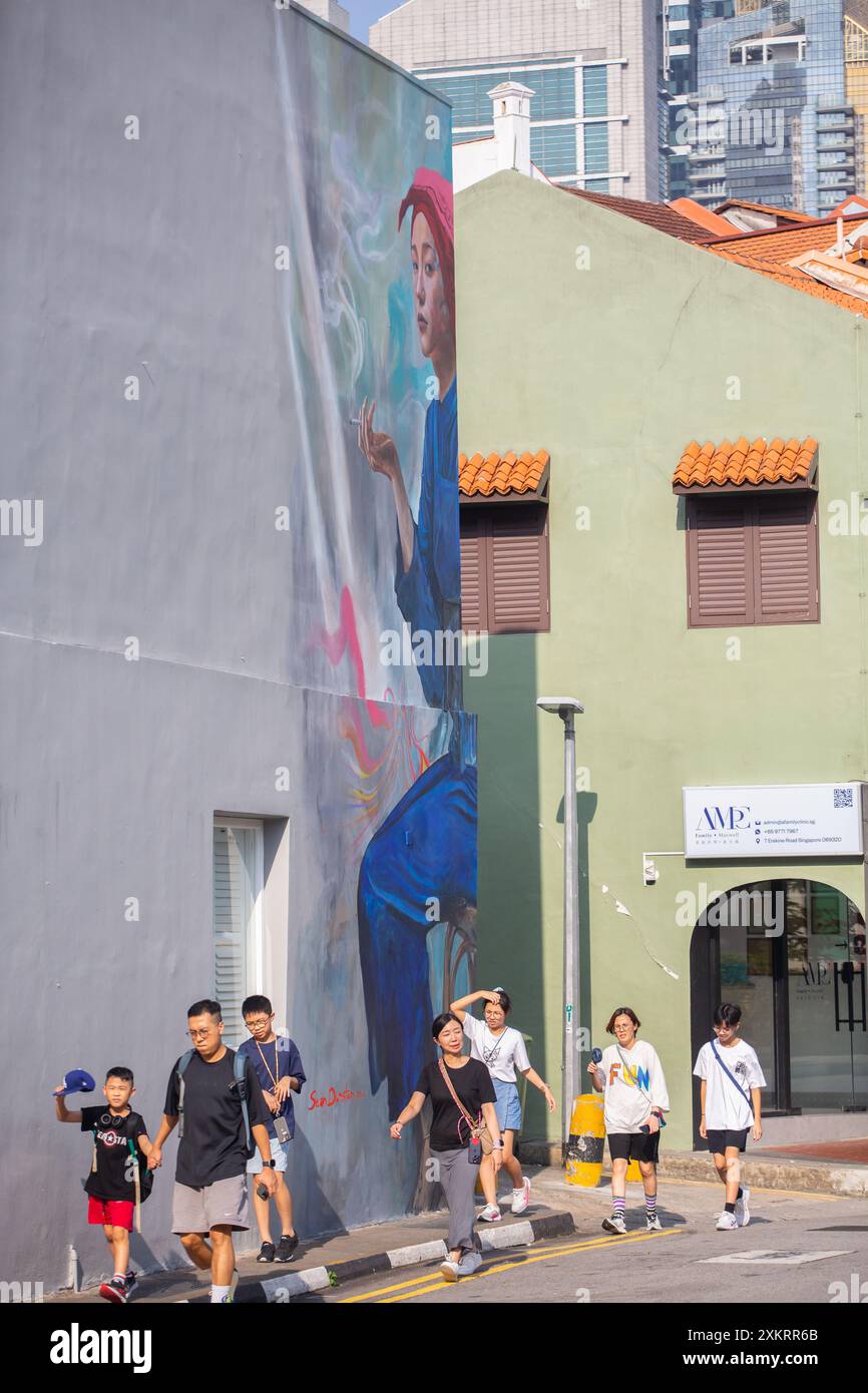 A group of Asian tourists walk past wall mural of a painted Samsui ...