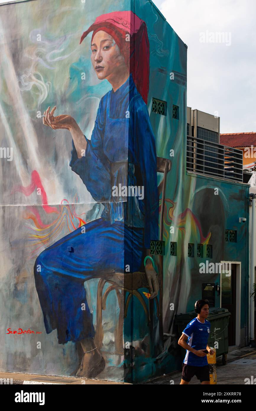 Vertical wall mural of a Samsui woman. a man jogging past the area ...
