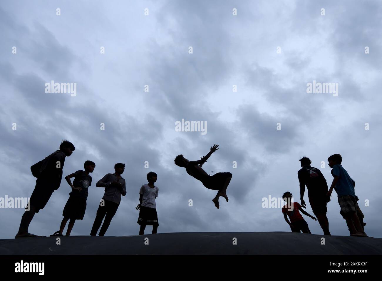 Young People enjoy the weather as dark monsoon clouds gather in the sky ...