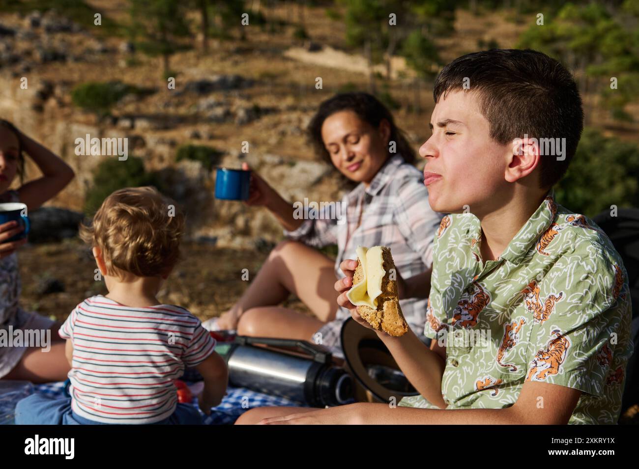 Family picnic in nature with children enjoying sandwiches and drinks ...