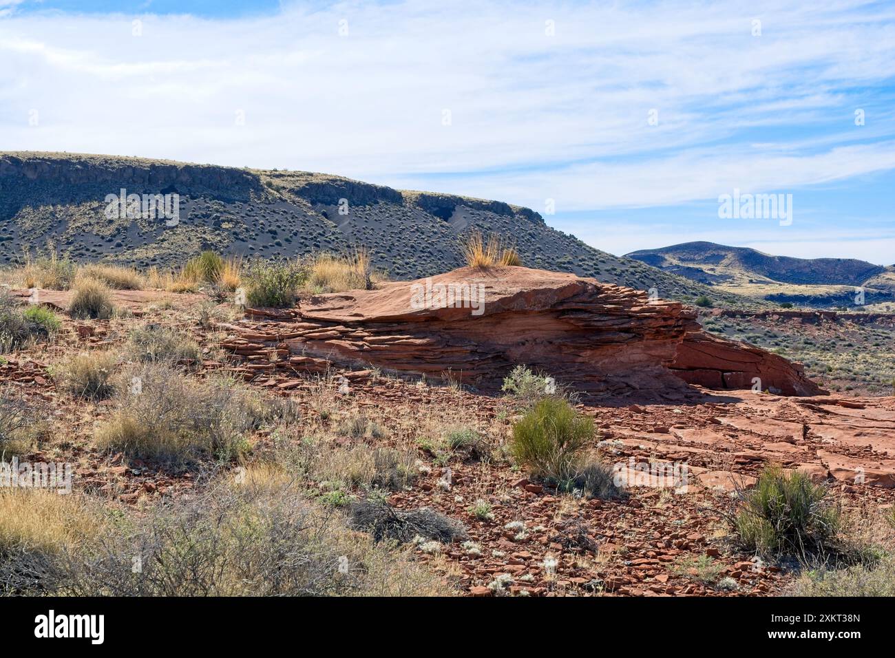 Eroding layered sandstone uplift before black volcanic cinder deposit ...