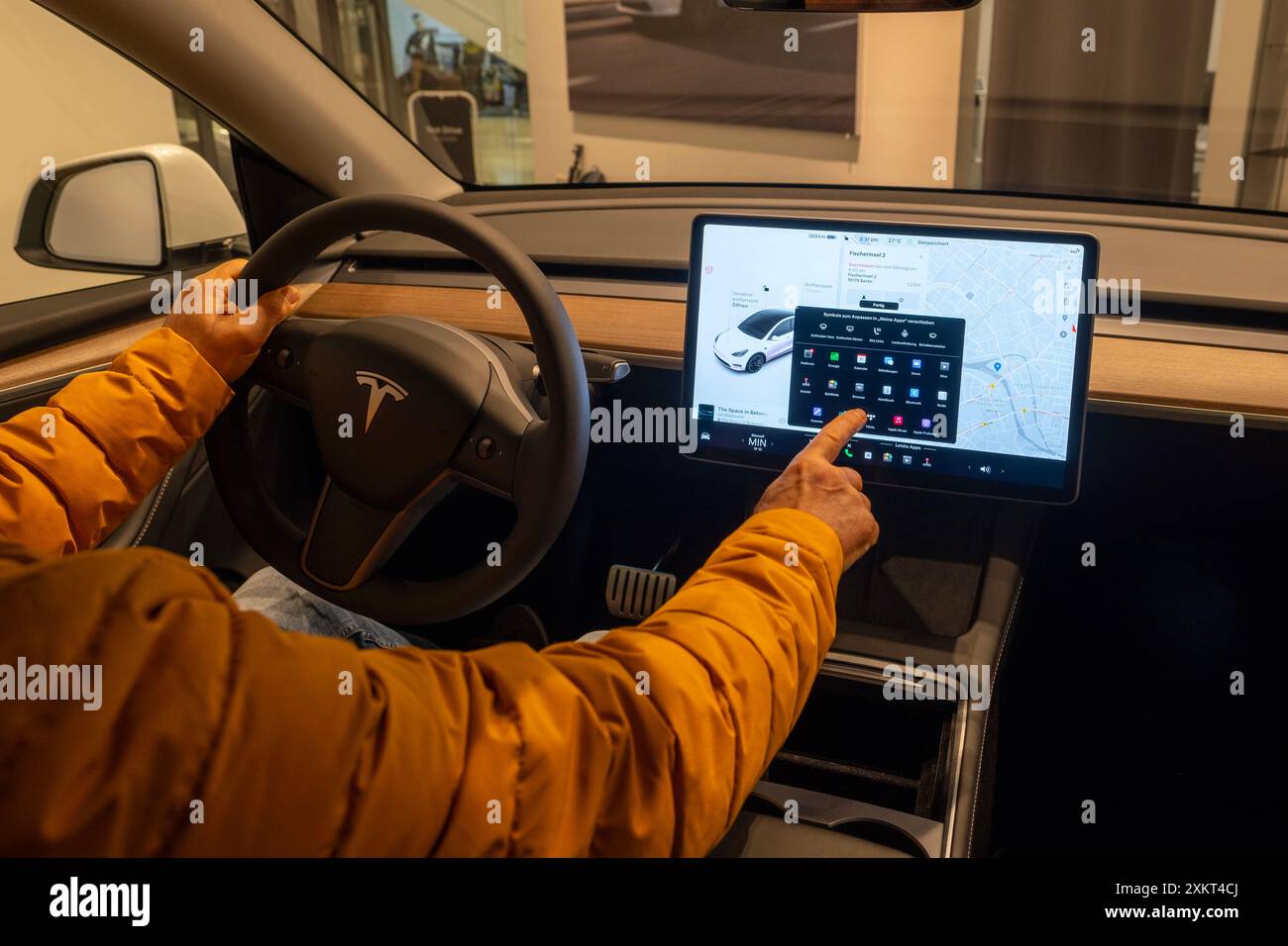 Close-up male hands uses display, gripping steering wheel Tesla model Y ...