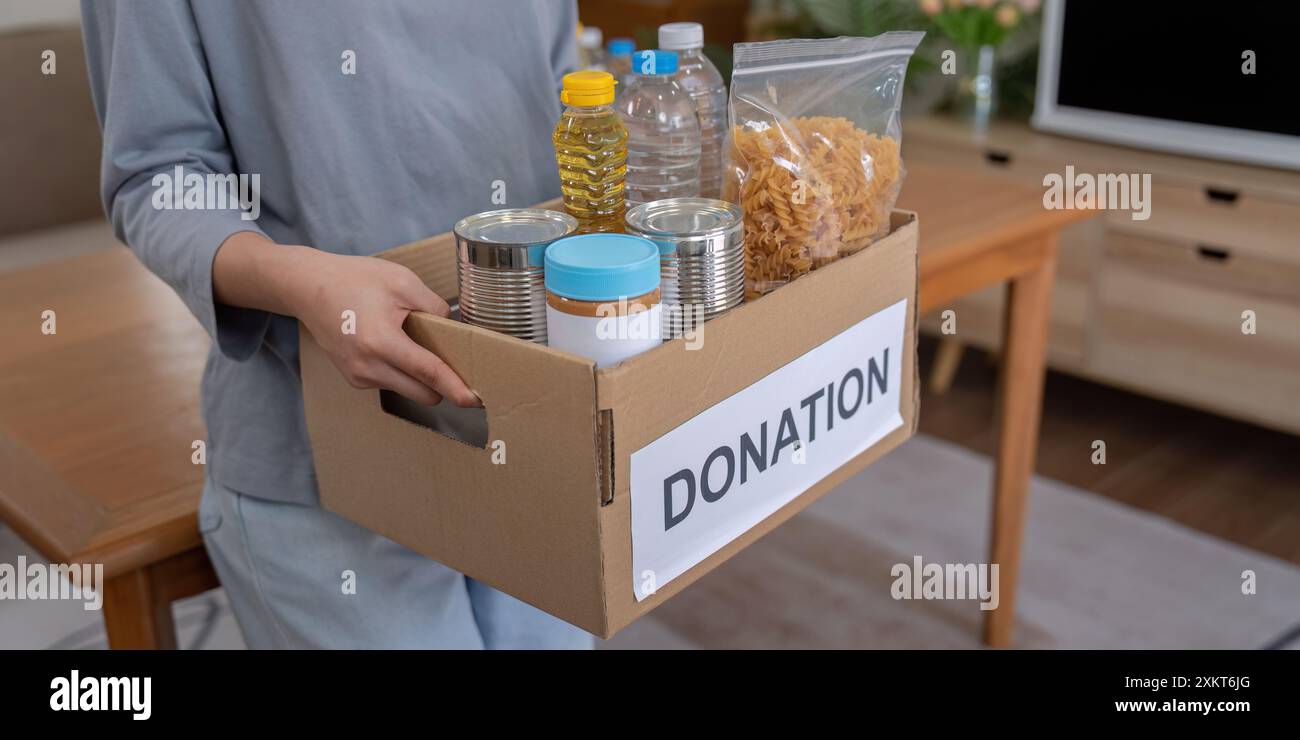 Person Holding a Donation Box Filled with Food Items and Essential for ...