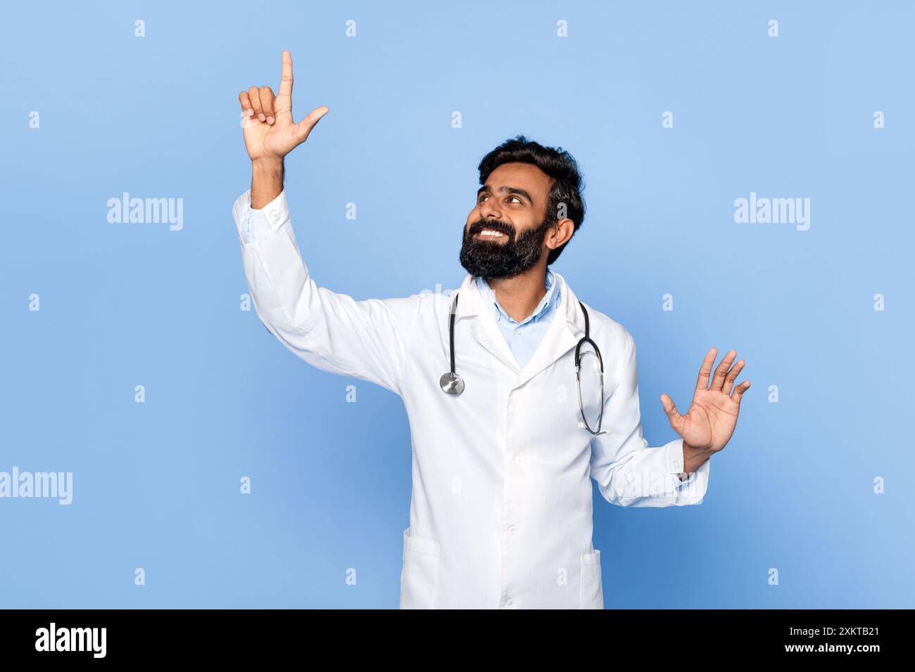 Indian man doctor with a beard is smiling and pointing upward with his ...