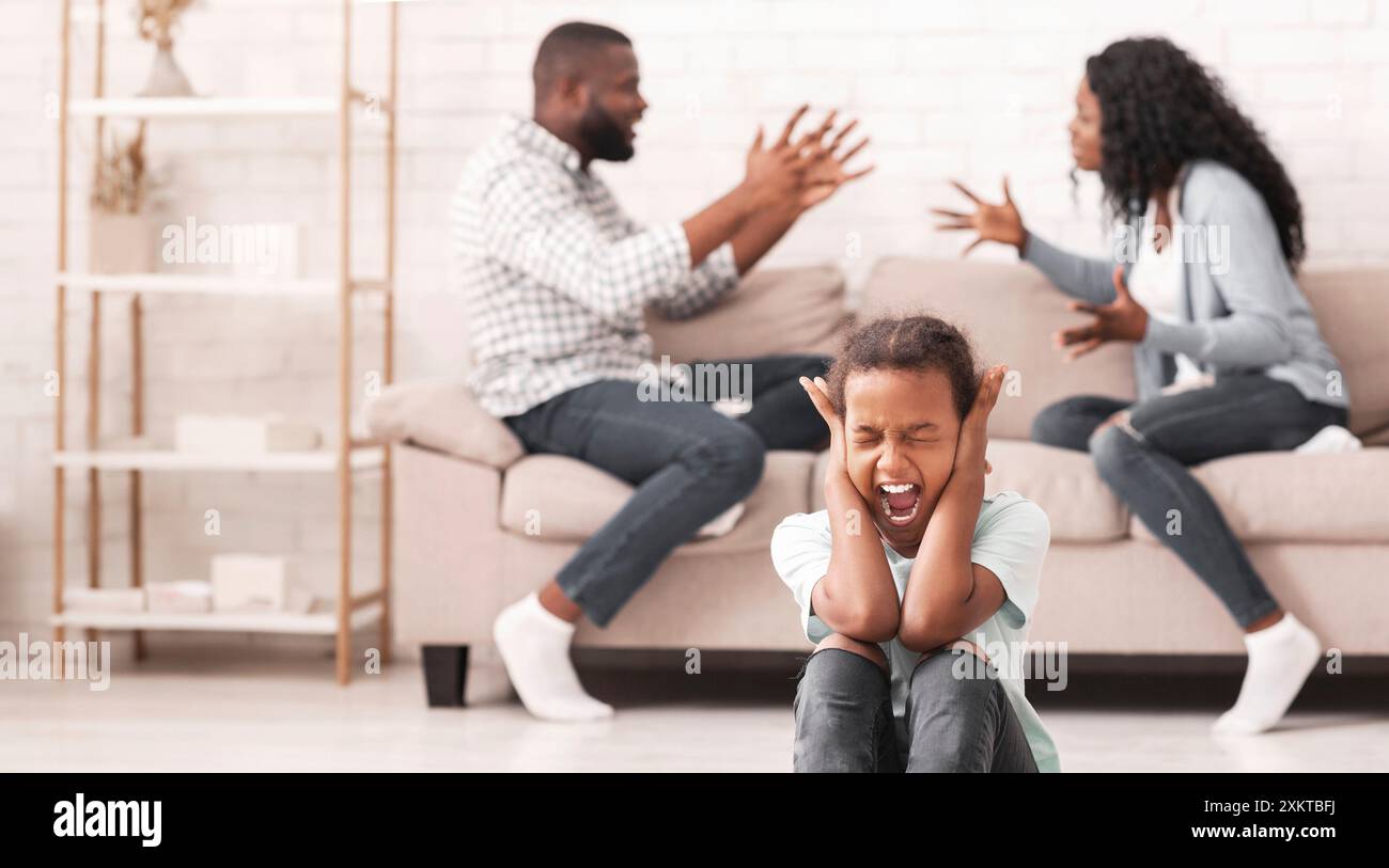 Defensive reaction. Upset little black girl sitting on floor, yelling ...