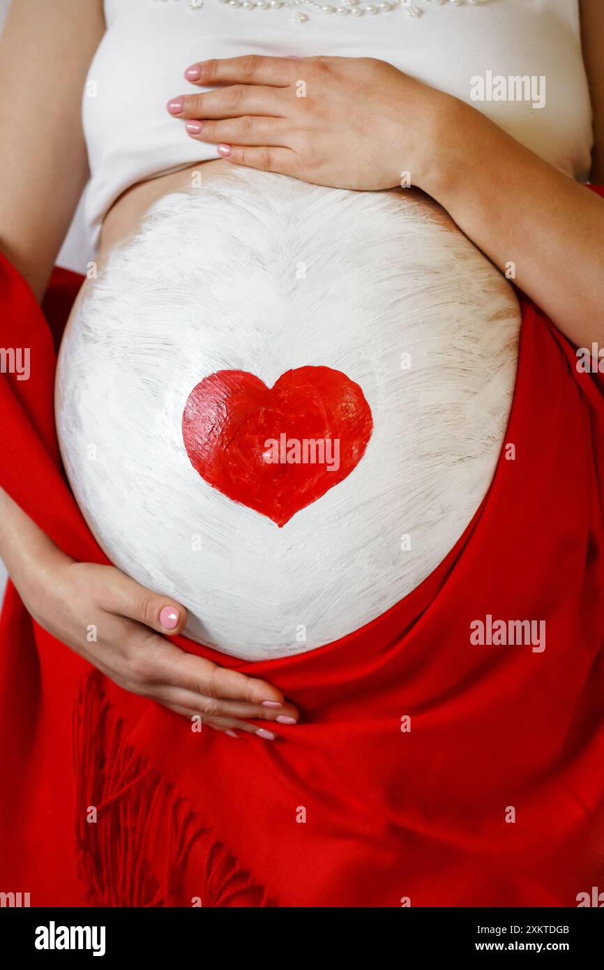 Pregnant Caucasian woman pattern red heart on belly hugging hands ...