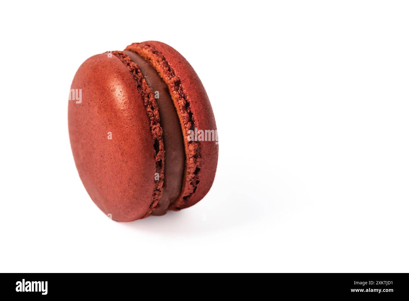 A single, red macaron with a strawberry filling is shown in a close-up ...