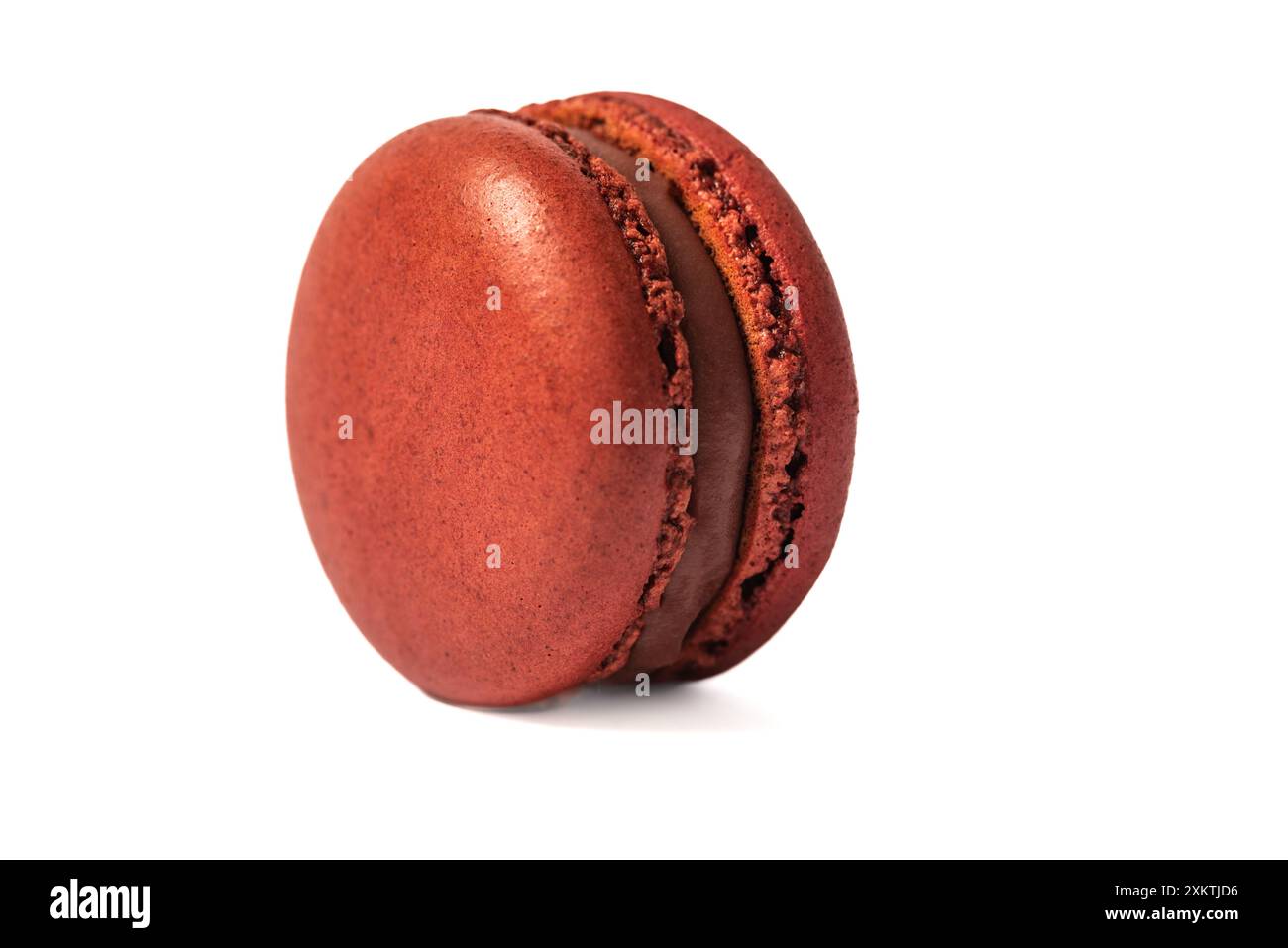 A single, red macaron with a strawberry filling is shown in a close-up ...