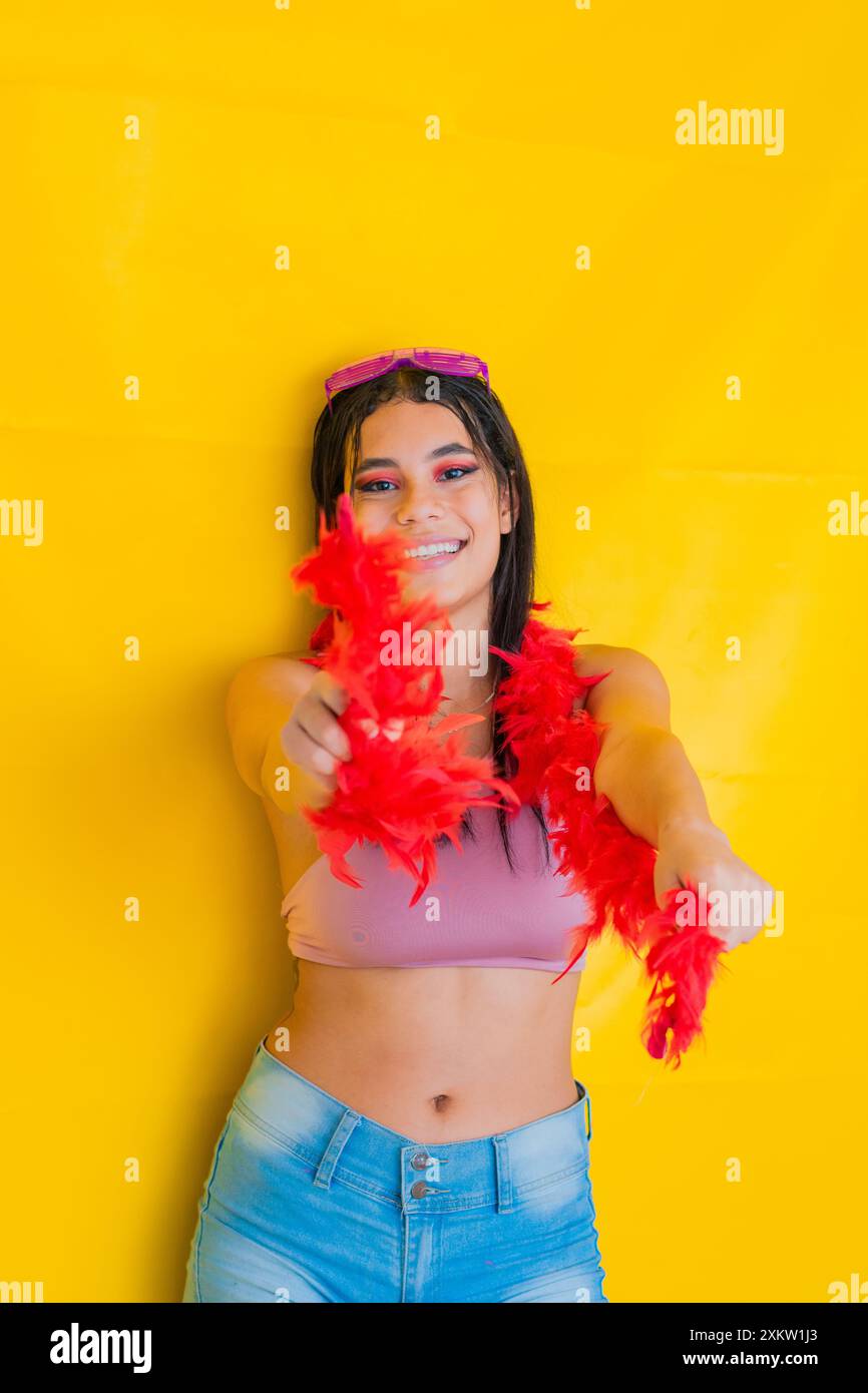 brunette latina woman, dancing with a strip of red feathers on a yellow ...