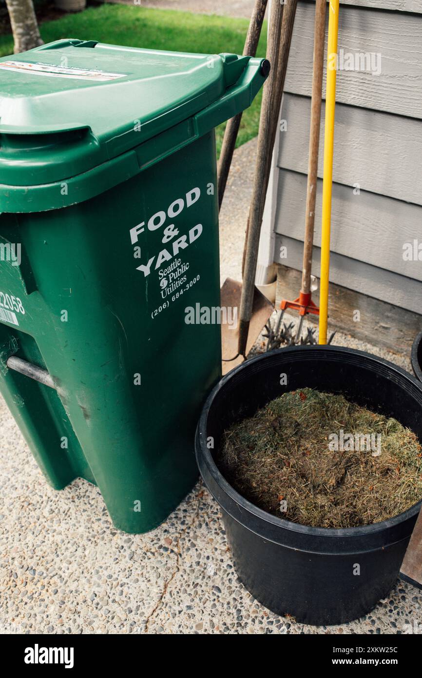 green residential compost bin by yard waste, gardening tools Stock ...