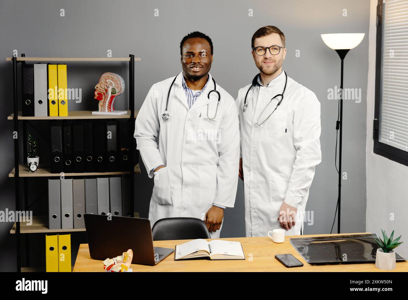 Two men in white lab coats standing together near desk Stock Photo - Alamy