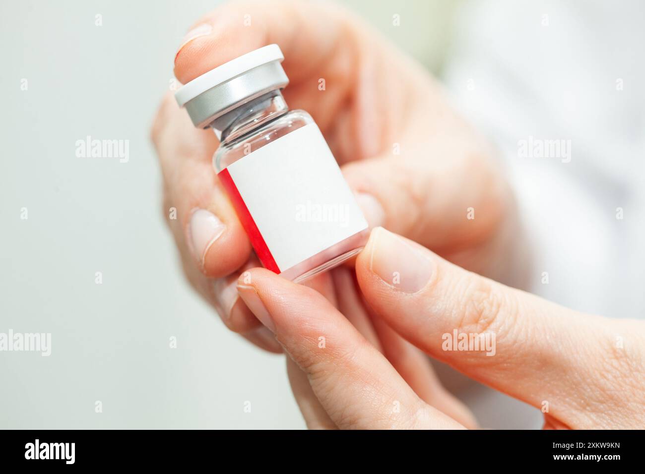 Close up of doctor hands while holding a vial of an injectable liquid ...
