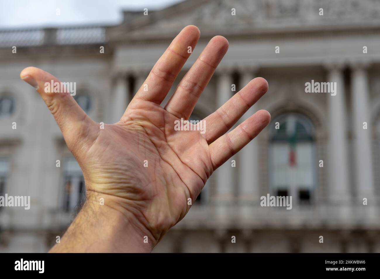 Left palm raised in the air under blurred building background Stock ...
