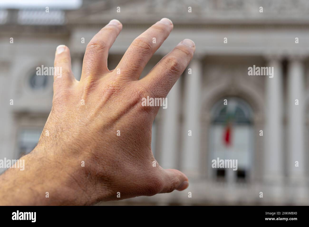 Left hand raised in the air grabbing the blurred background of building ...