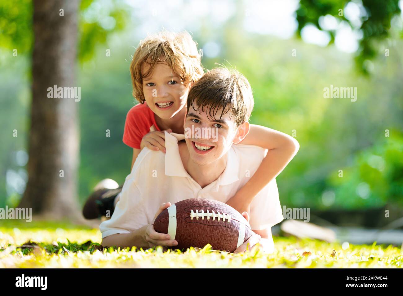 Family playing American football. Kids play rugby in sunny summer park ...