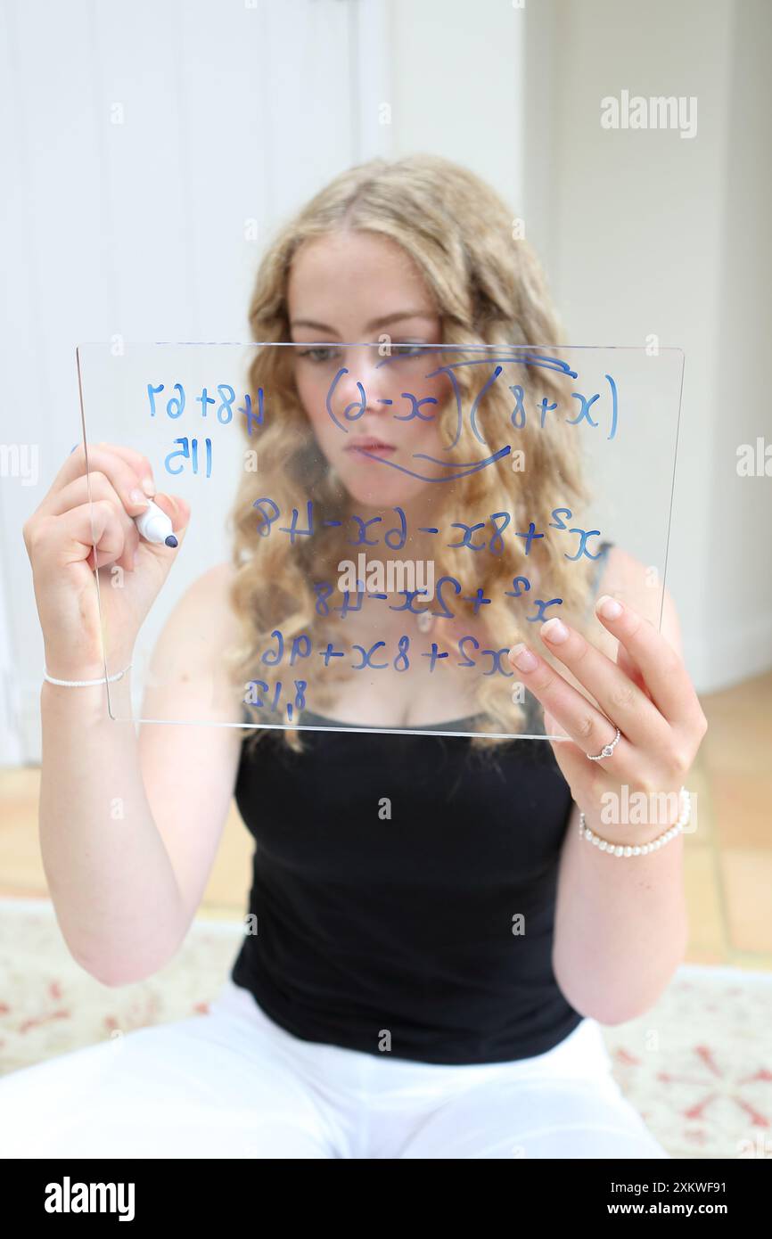 Girl doing maths math sittng on floor writing on whiteboard with pen ...