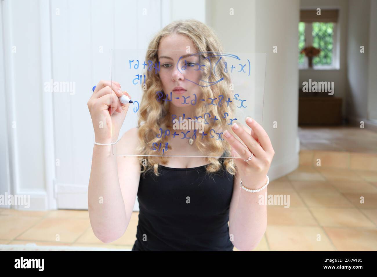 Girl doing maths math sittng on floor writing on whiteboard with pen ...