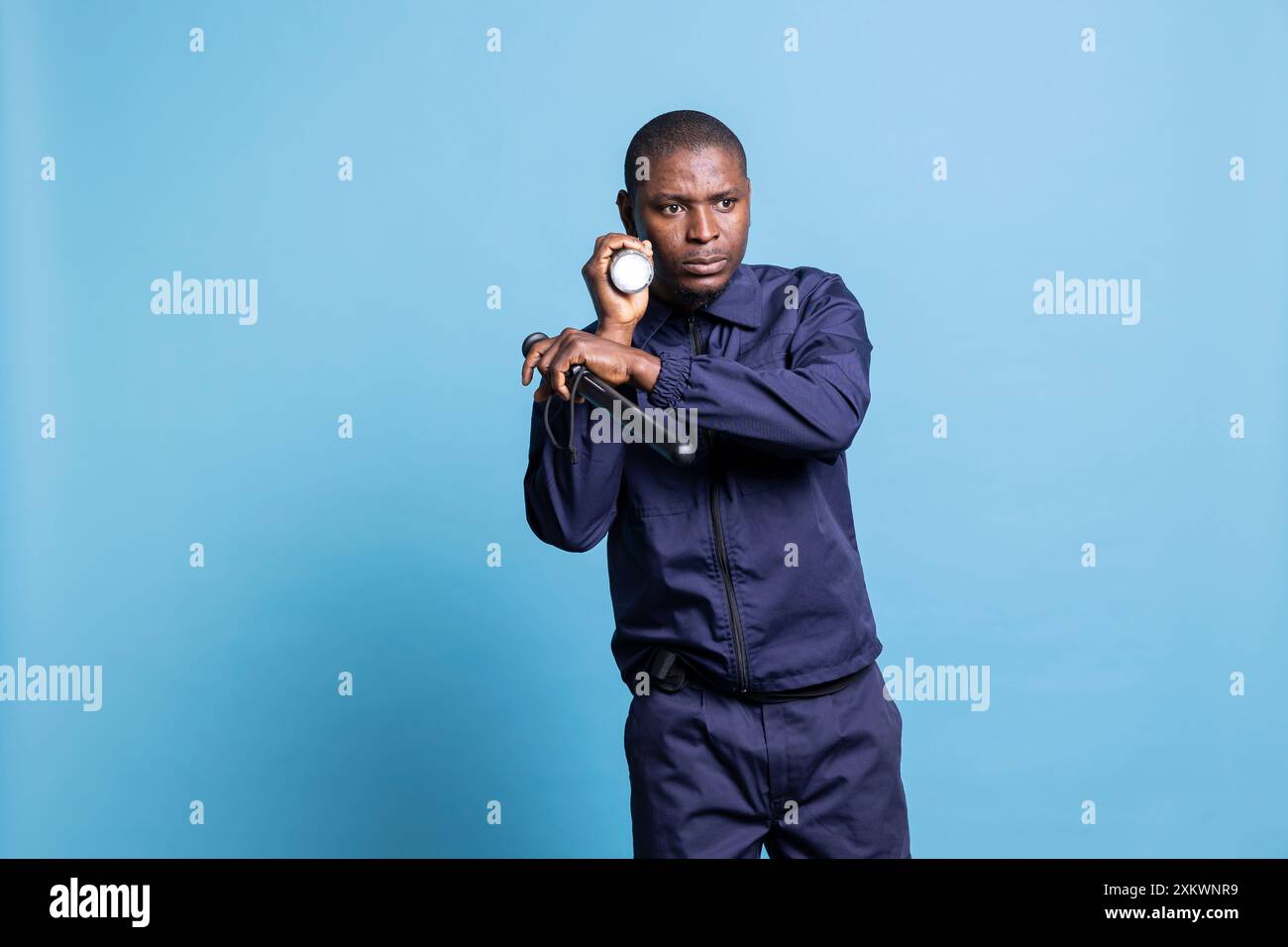 Security guard patrolling the premises with a flashlight and baton, working on protecting and ...