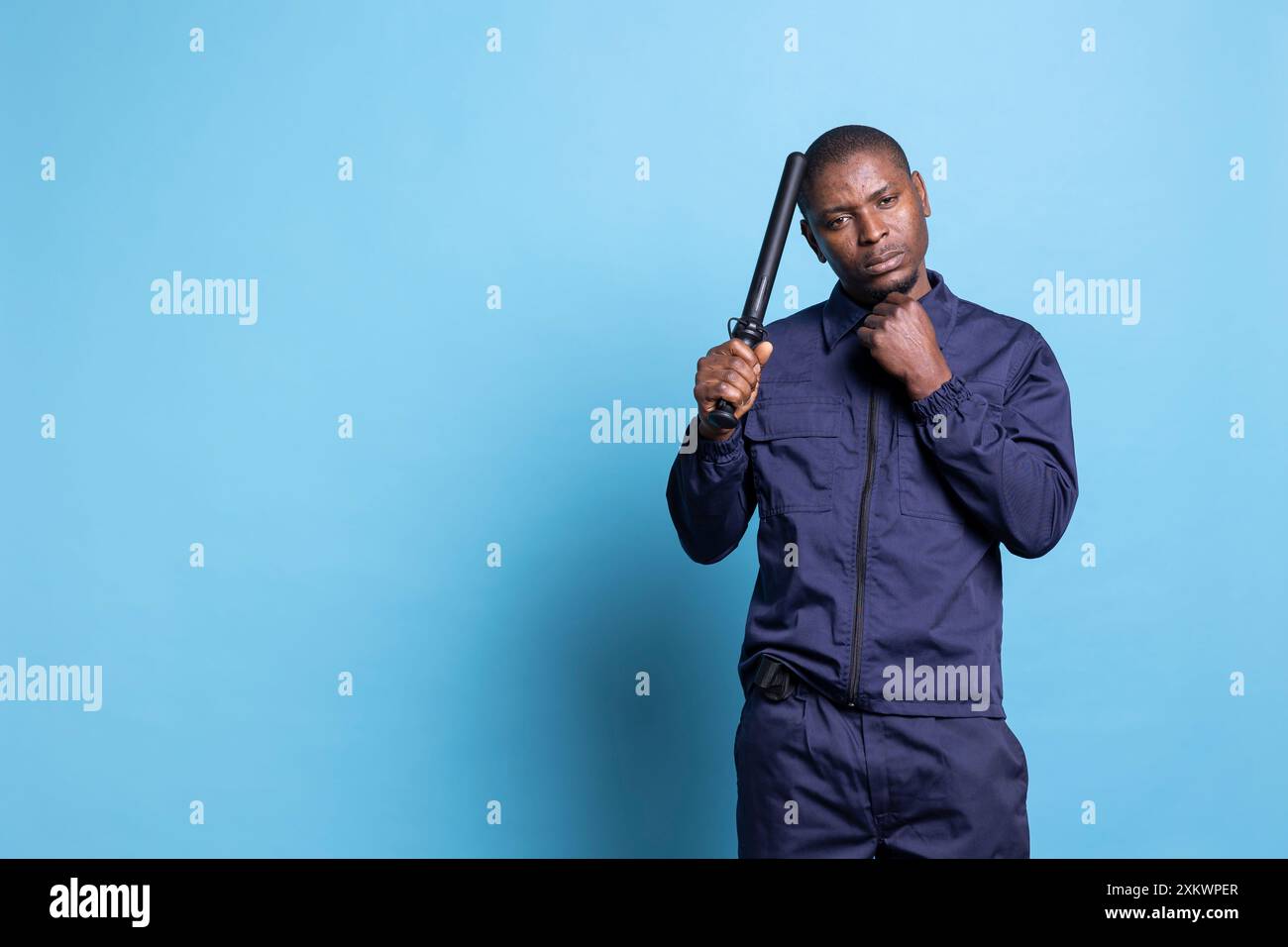 Security officer poses with a police baton and his fist clenched ...