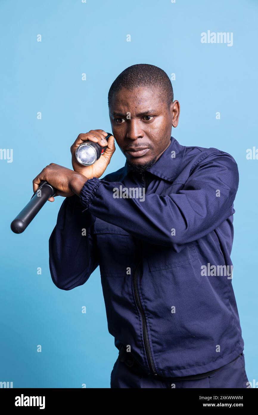 Trained security officer inspecting the premises with a flashlight and ...