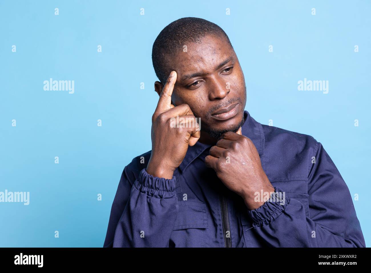 Pensive security guard thinking of ways to ensure wellbeing on camera ...