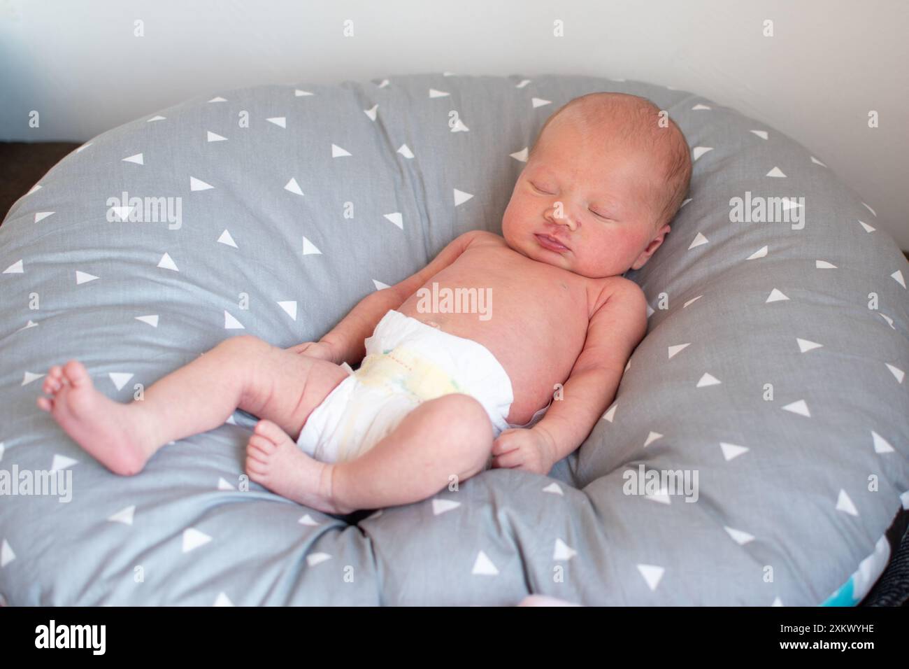 Little newborn baby sleeping on a baby lounger in a diaper. Napping ...