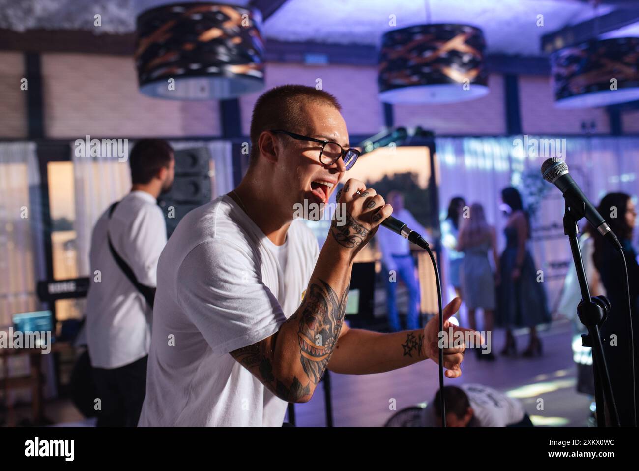 soloist on stage at a concert singing into a microphone in the rays of ...