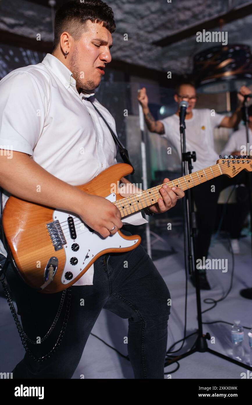 guy musician plays the electric guitar at a concert under stage ...