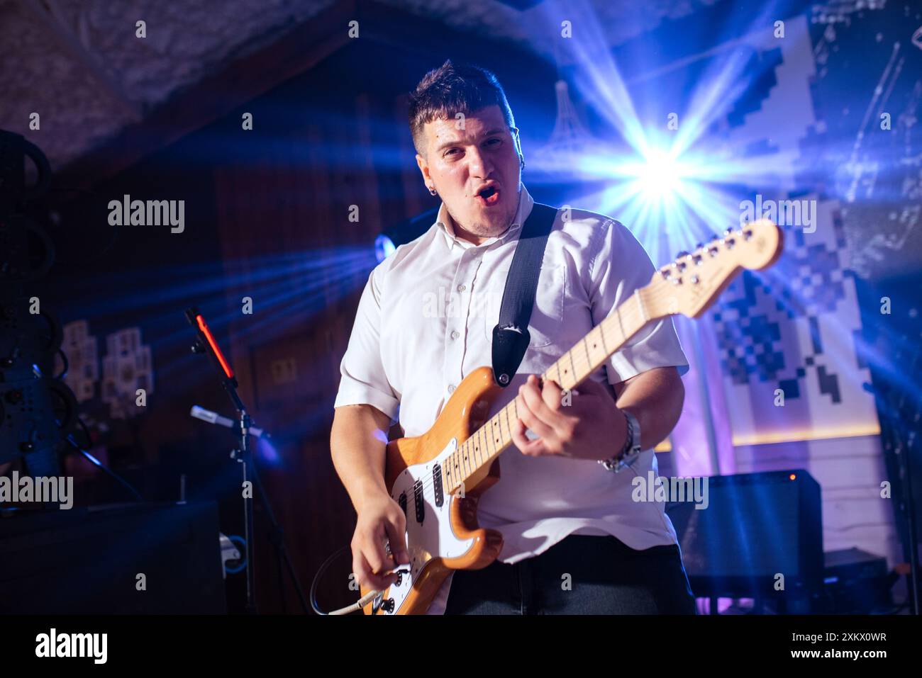 guy musician plays the electric guitar at a concert under stage ...