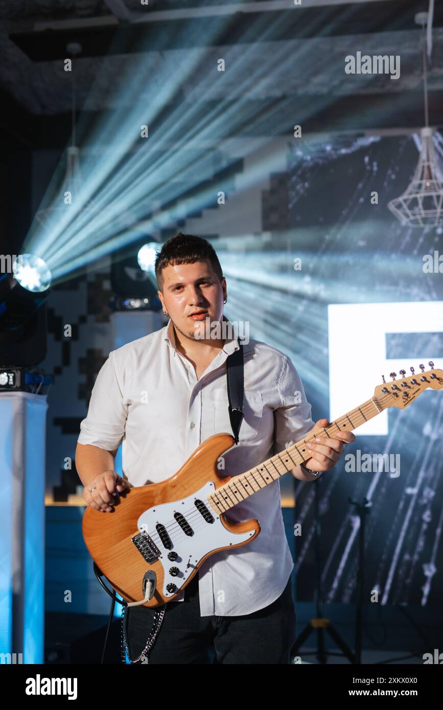 guy musician plays the electric guitar at a concert under stage ...