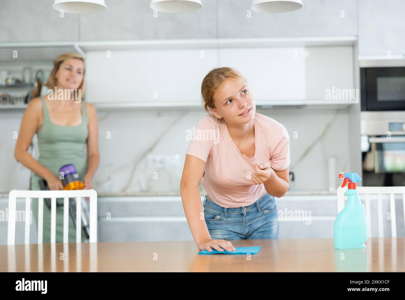 Teen girl help mother and wash dining table in kitchen, blurry mom ...