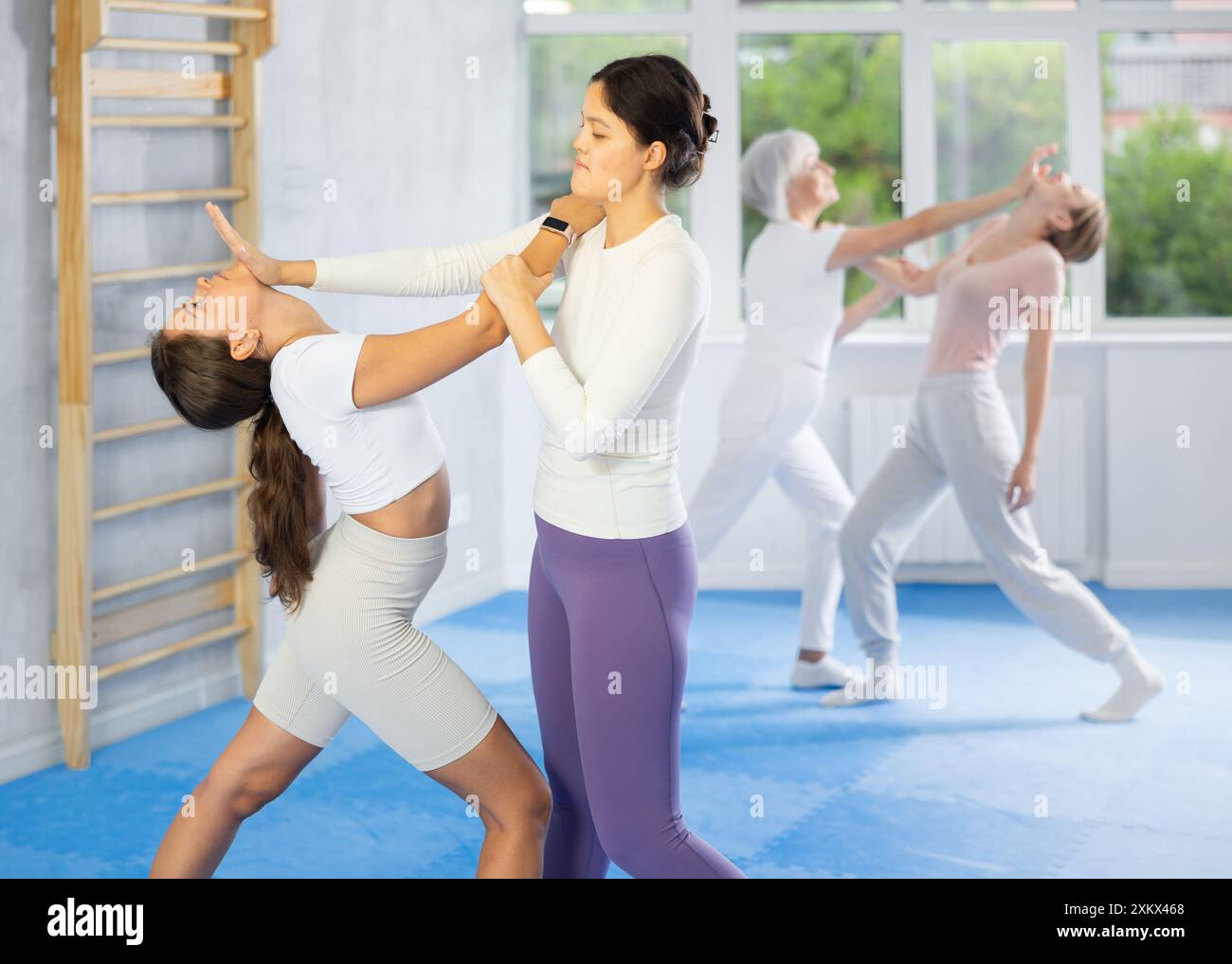 Woman and girl in gym perform basic elements of krav maga self-defense ...