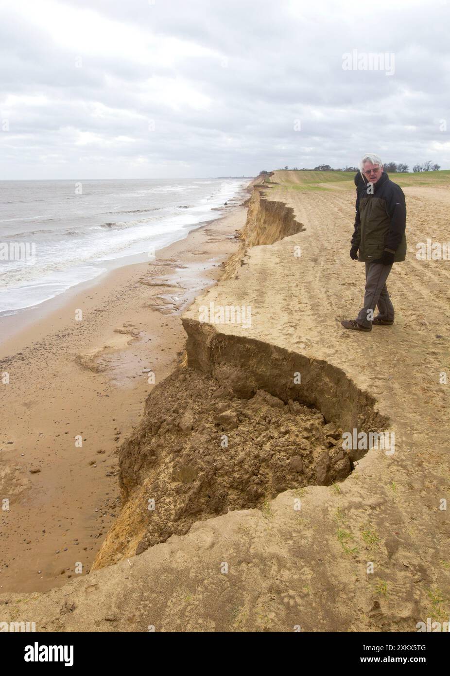 Walker along the edge of Cliff erosion Stock Photo - Alamy