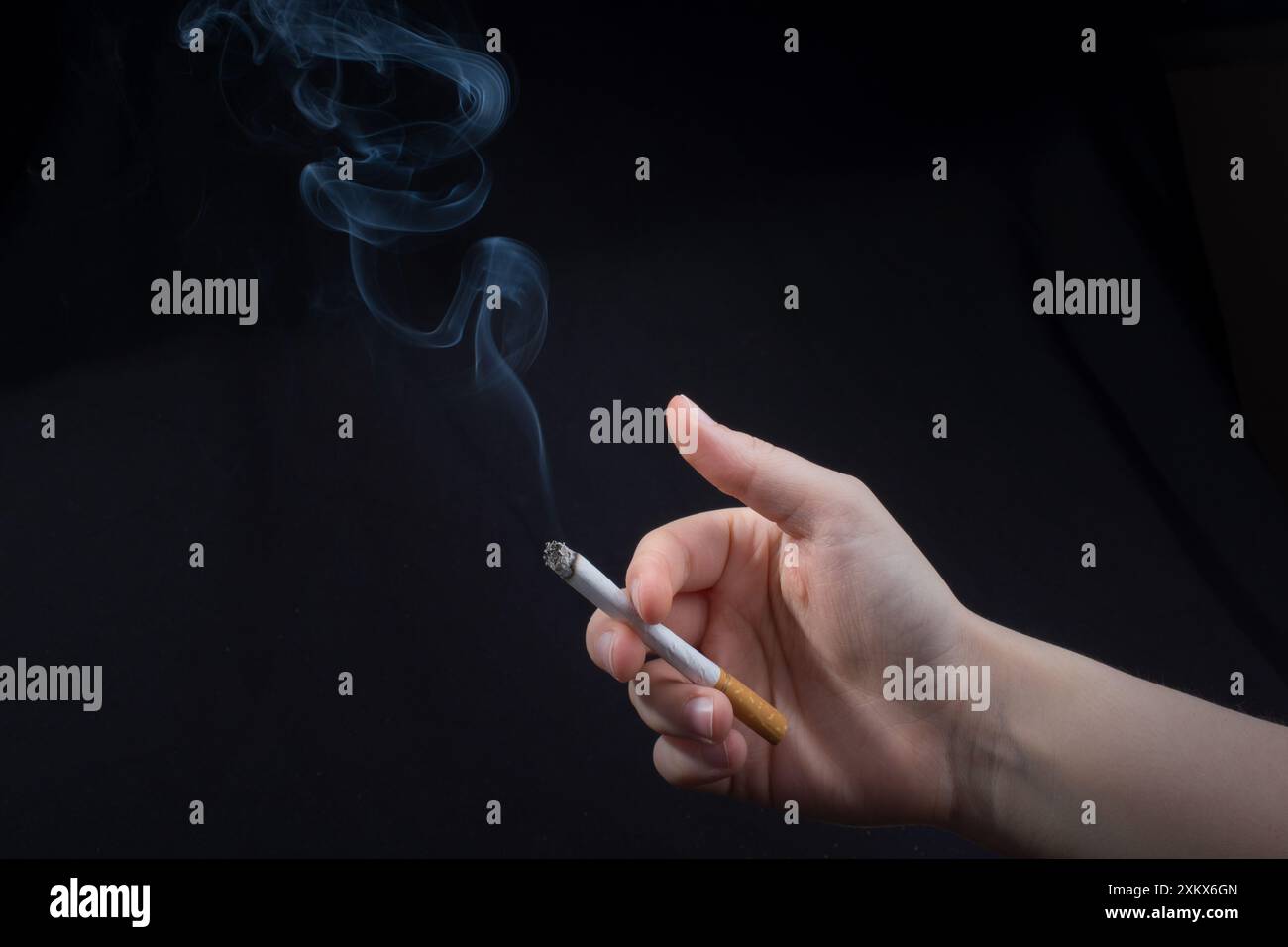 Hand is holding smoking cigarette with smoke around Stock Photo - Alamy