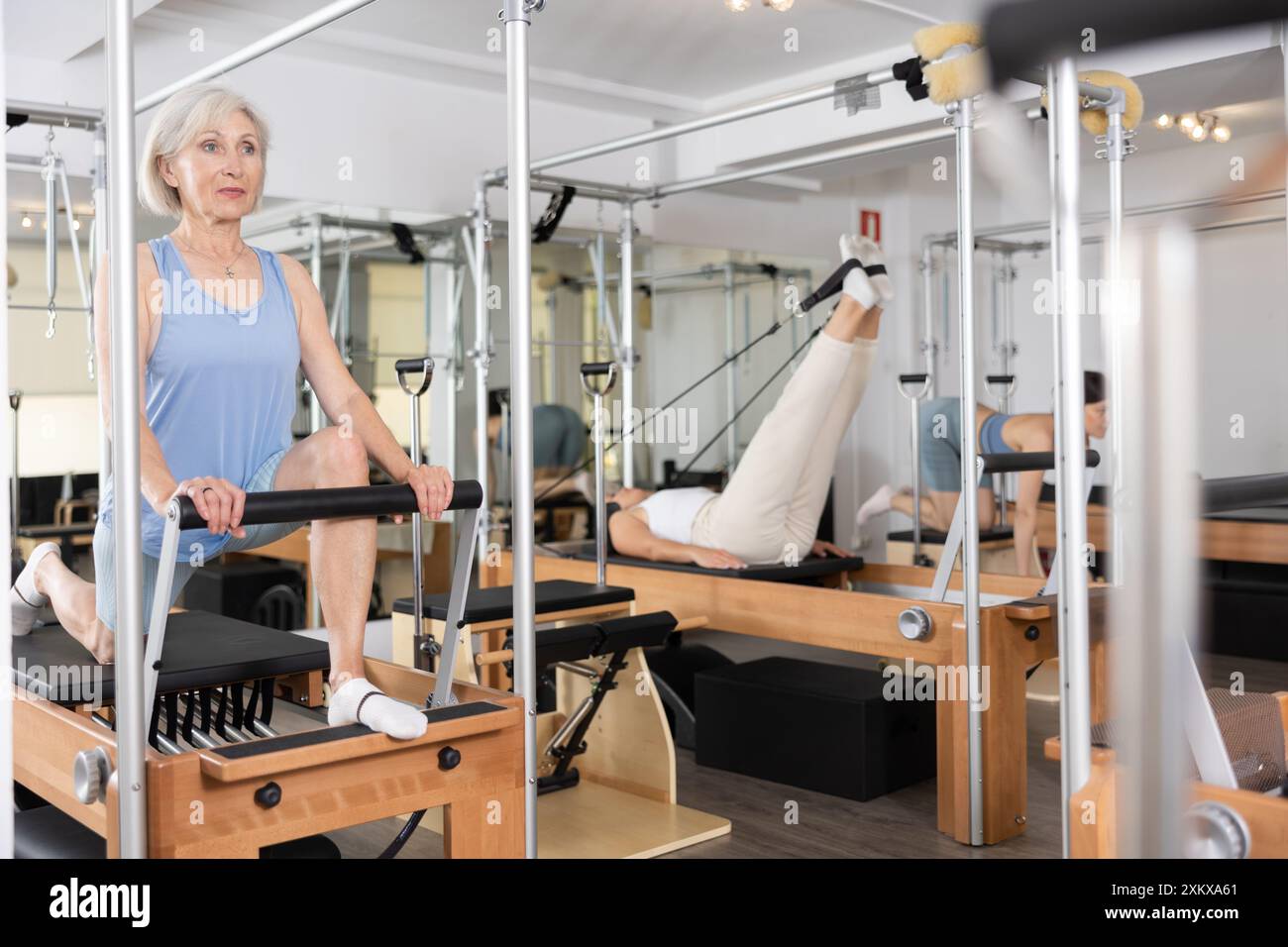 Elderly woman performing set of pilates exercises on reformer Stock ...