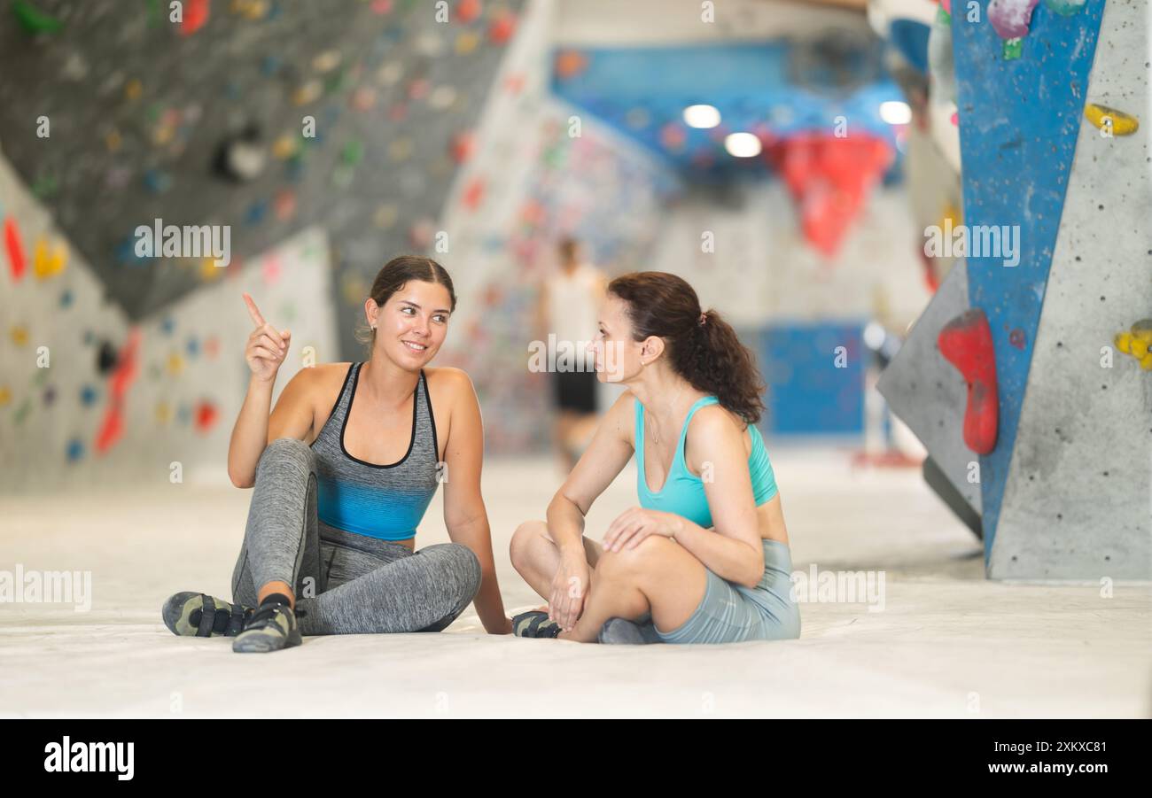 Two athletic women sit on floor and discuss options for climbing a ...