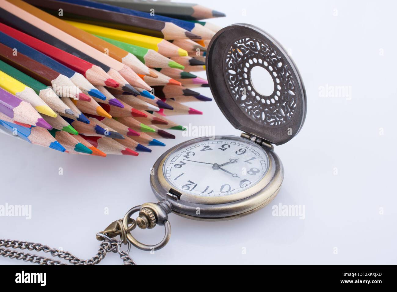 Retro style classic pocket watch and color pencils on white background ...
