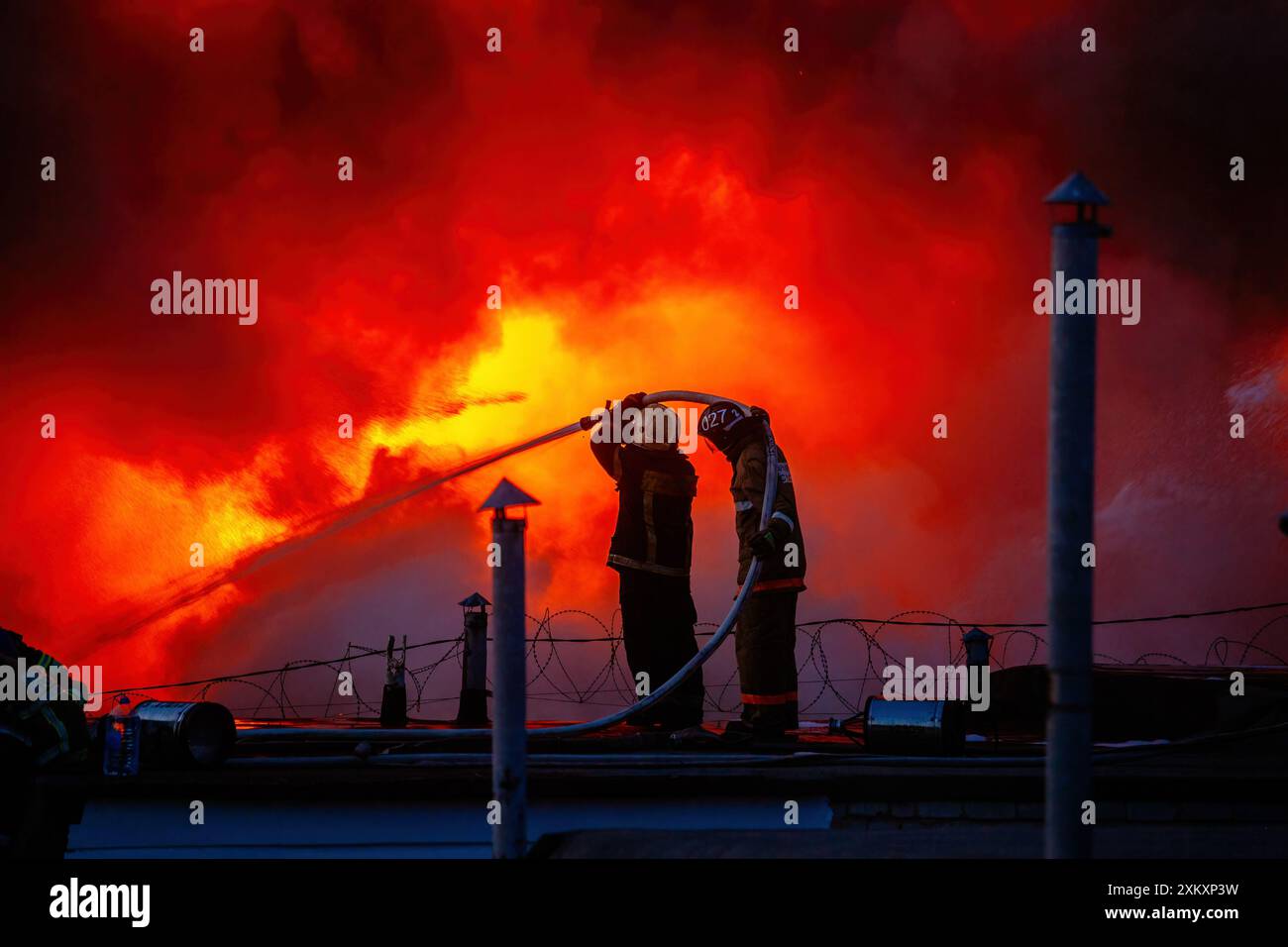 Firefighters extinguishing burning building on the roof Stock Photo - Alamy