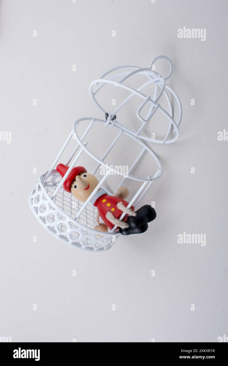 Metal cage and Little puppet pinocchio made of wood Stock Photo - Alamy