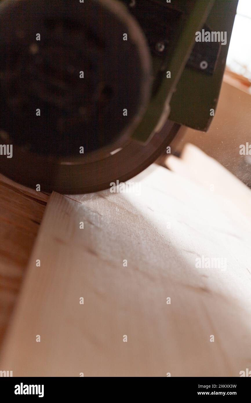 Carpenter using an electric sander on a wood plank in a workshop ...