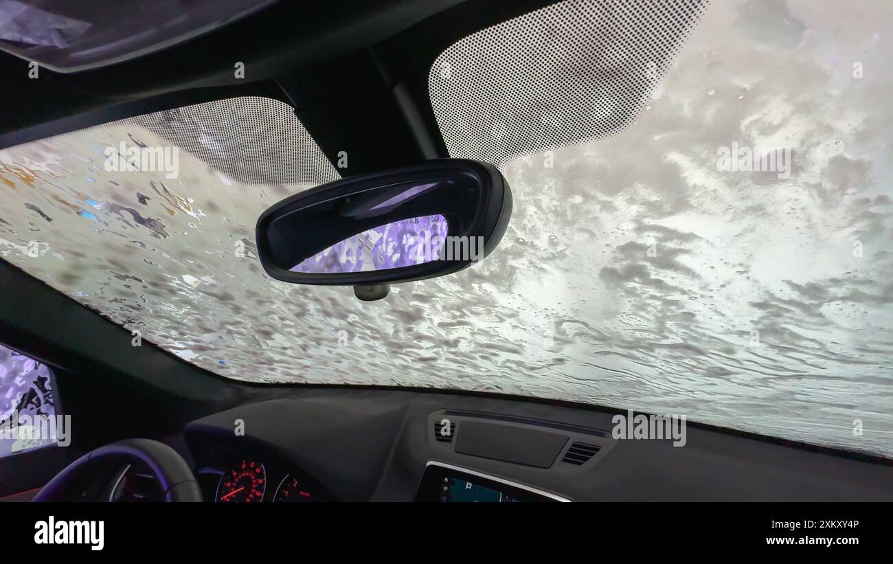Soapy water on the windshield of a car inside an automated car wash ...