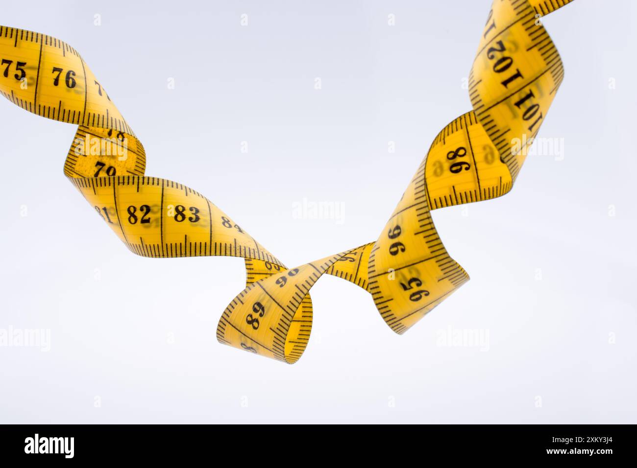 Yellow color measuring tape on a white background Stock Photo - Alamy