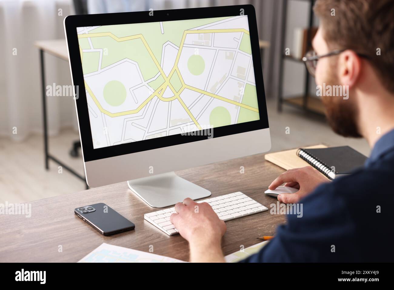 Cartographer working with cadastral map on computer at wooden table in ...