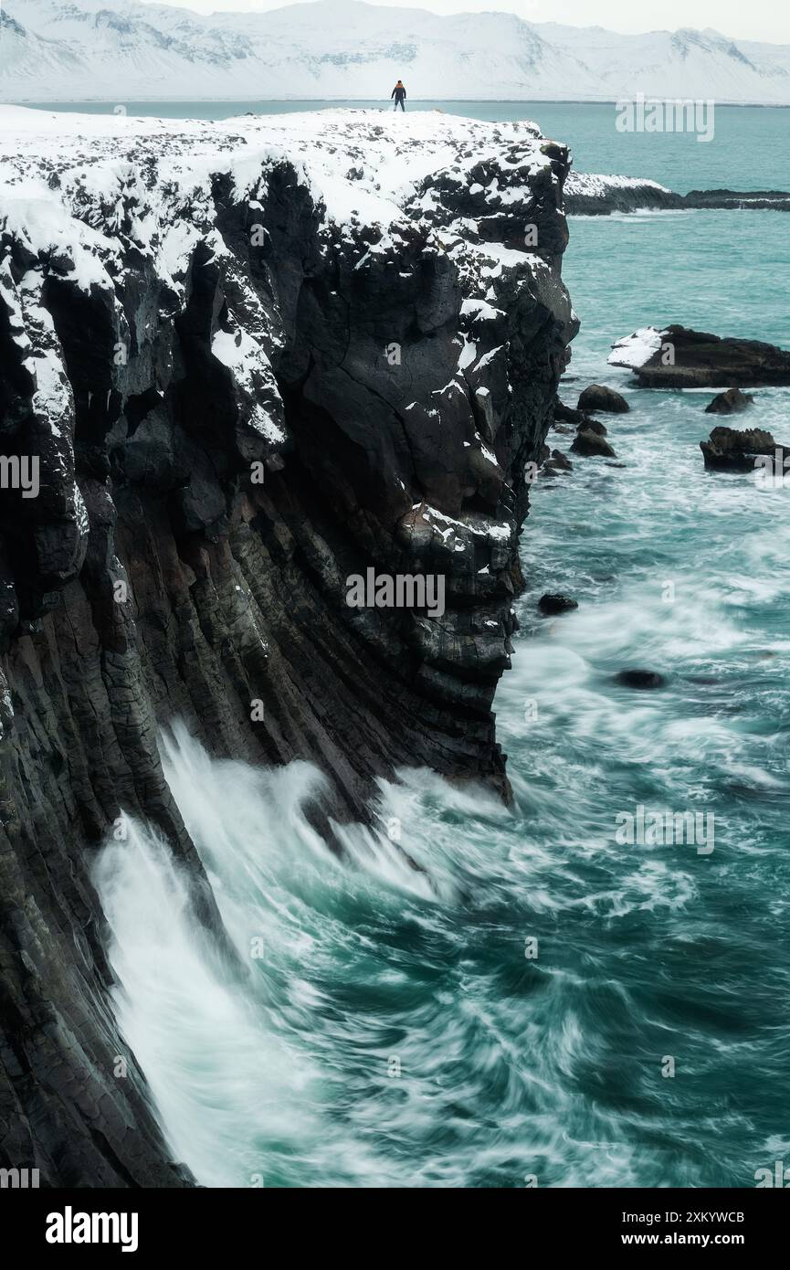 Lone hiker on top of basaltic volcano rock columns cliffs on the ...
