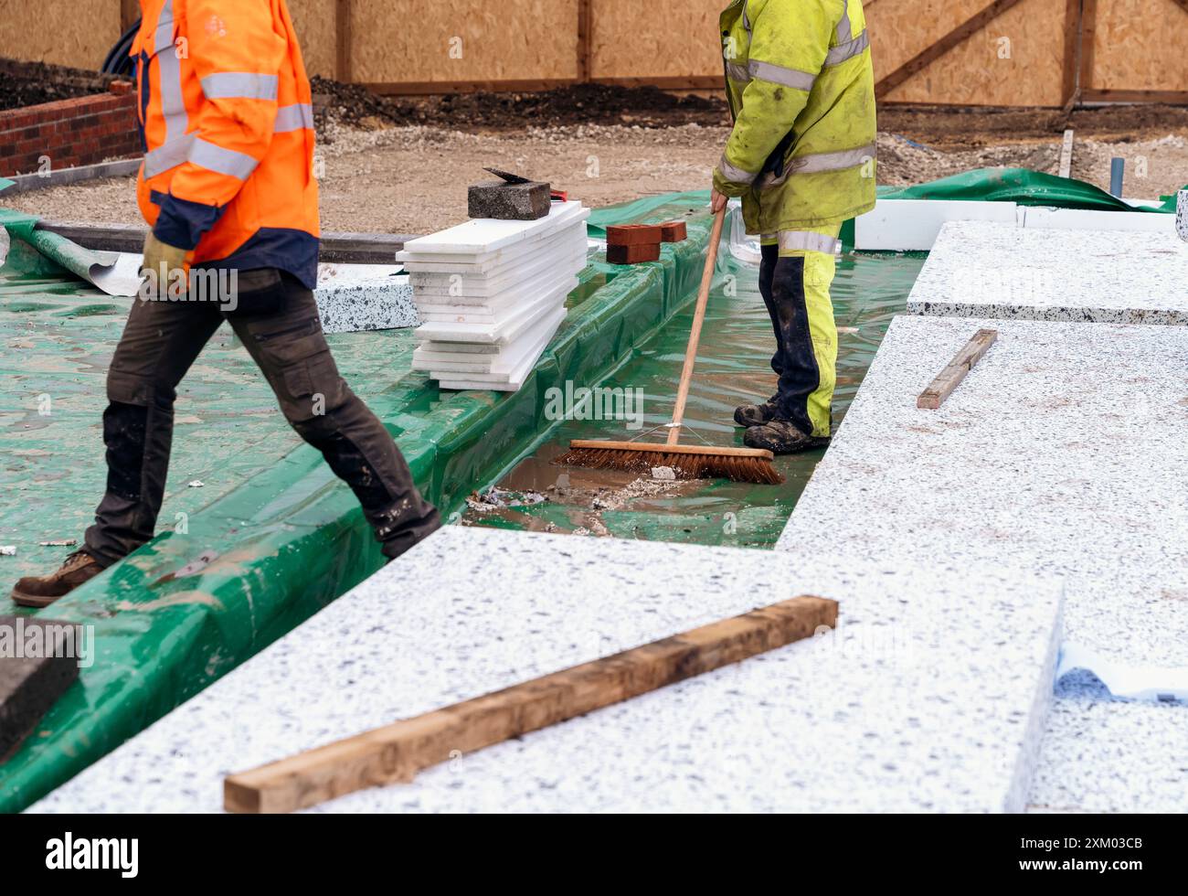 Builder placing polystyrene insulation boards on waterproofing membrane ...