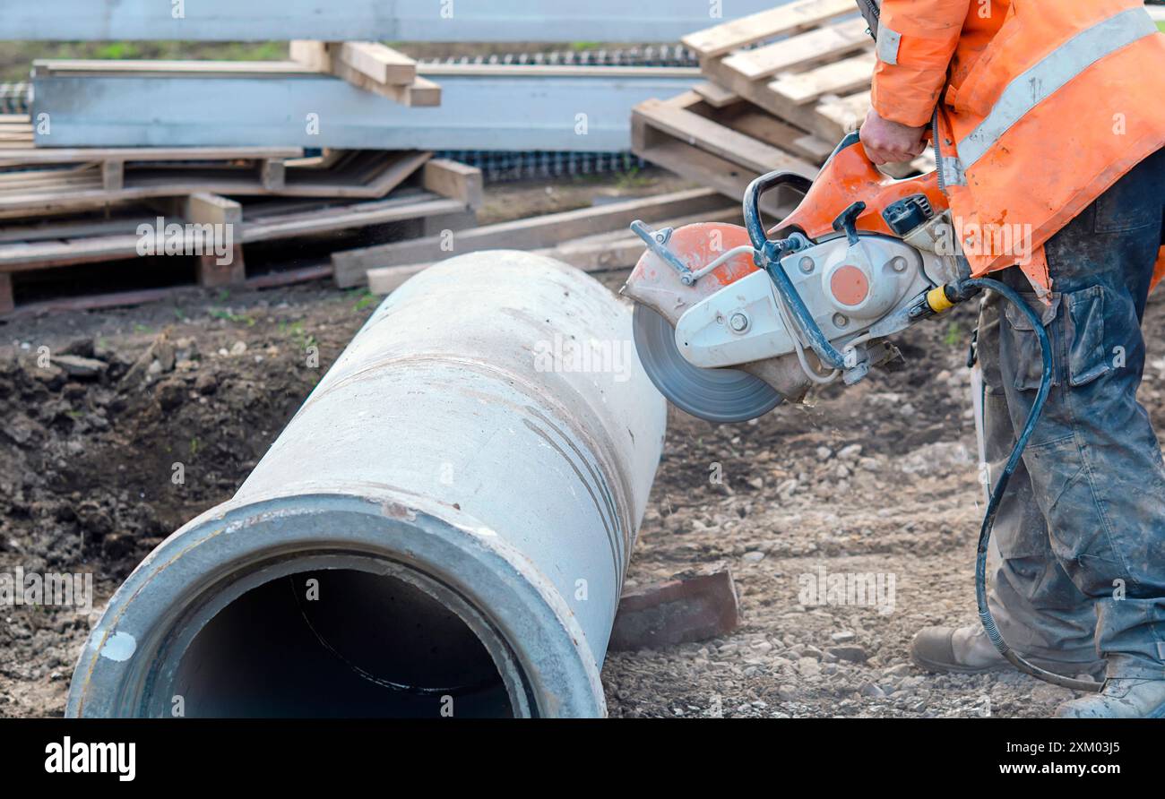 Construction worker cutting concrete pipe for drainage using a cut-off ...