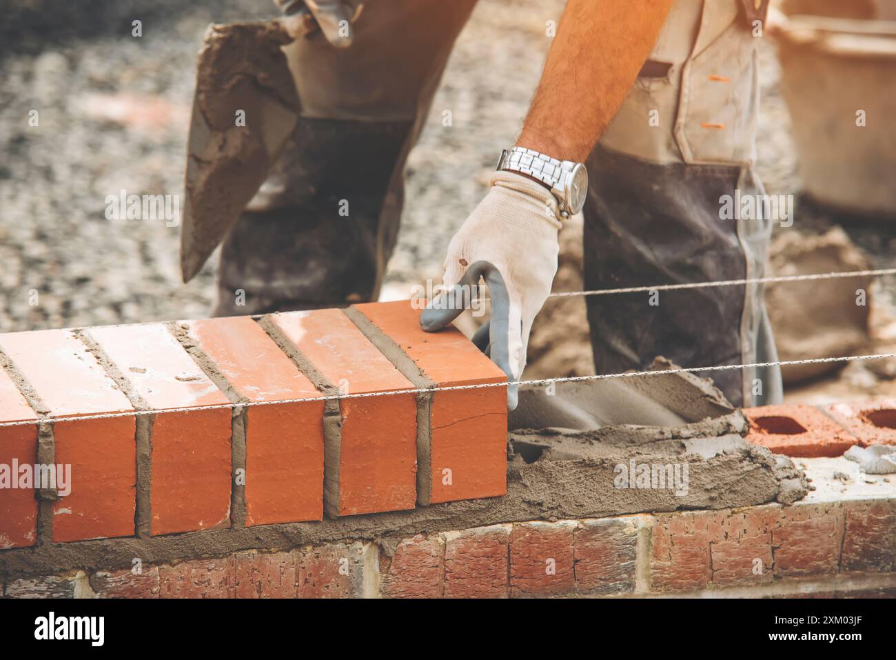Industrial bricklayer laying bricks on cement mix on construction site ...