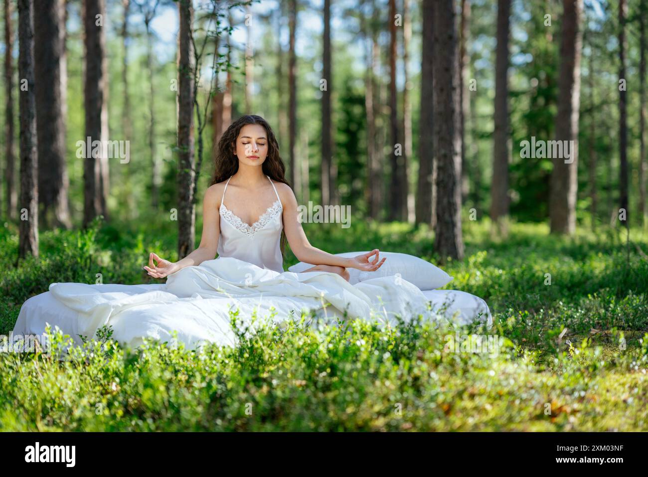 Young woman is resting on a mattress in the lotus position, in summer ...